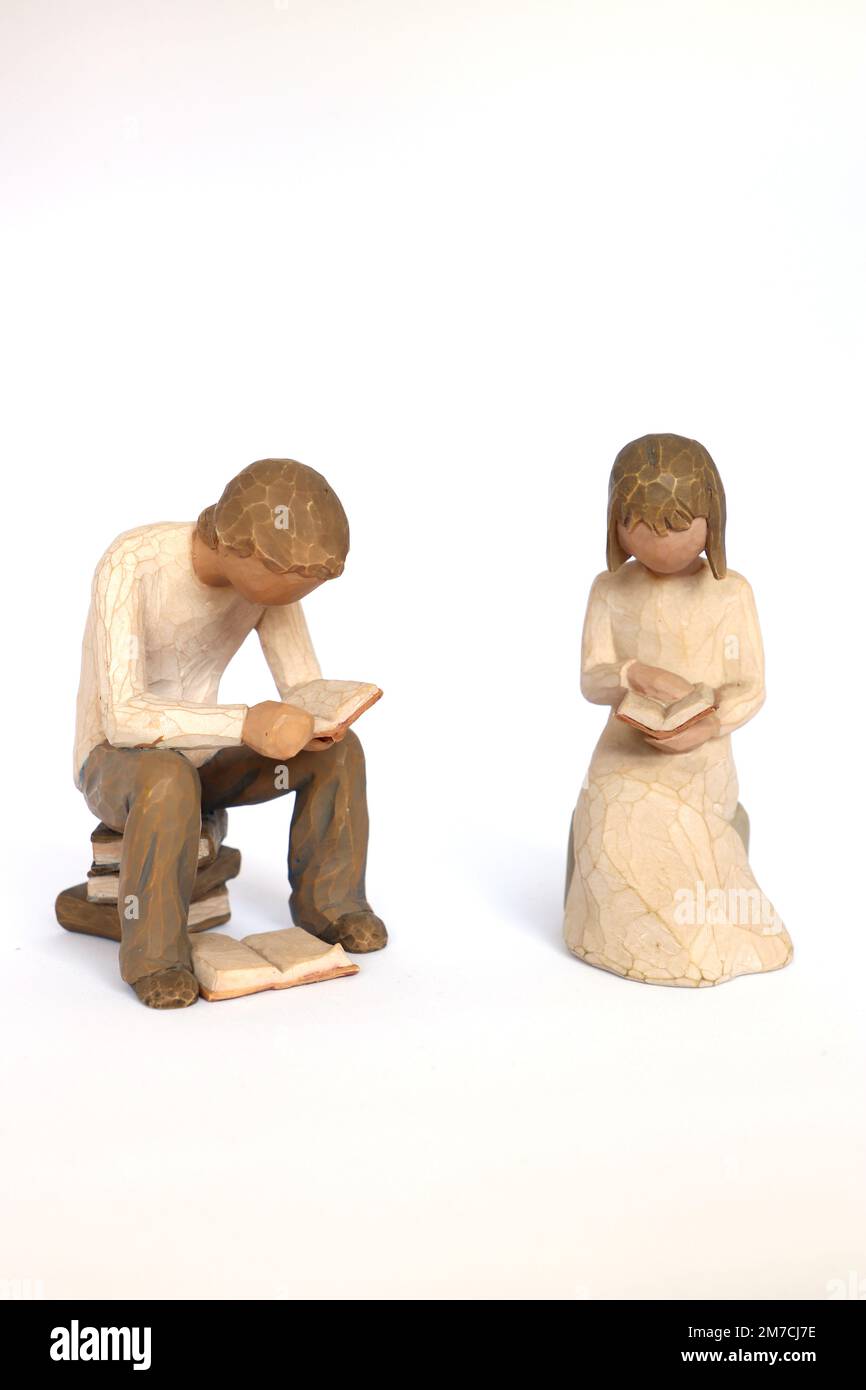 A man and woman sitting on books reading a book. Ornaments are from the ...