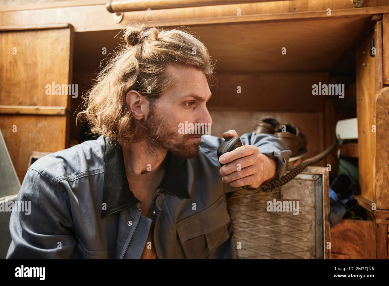 Side view portrait of bearded sailor talking by radio on boat, copy ...