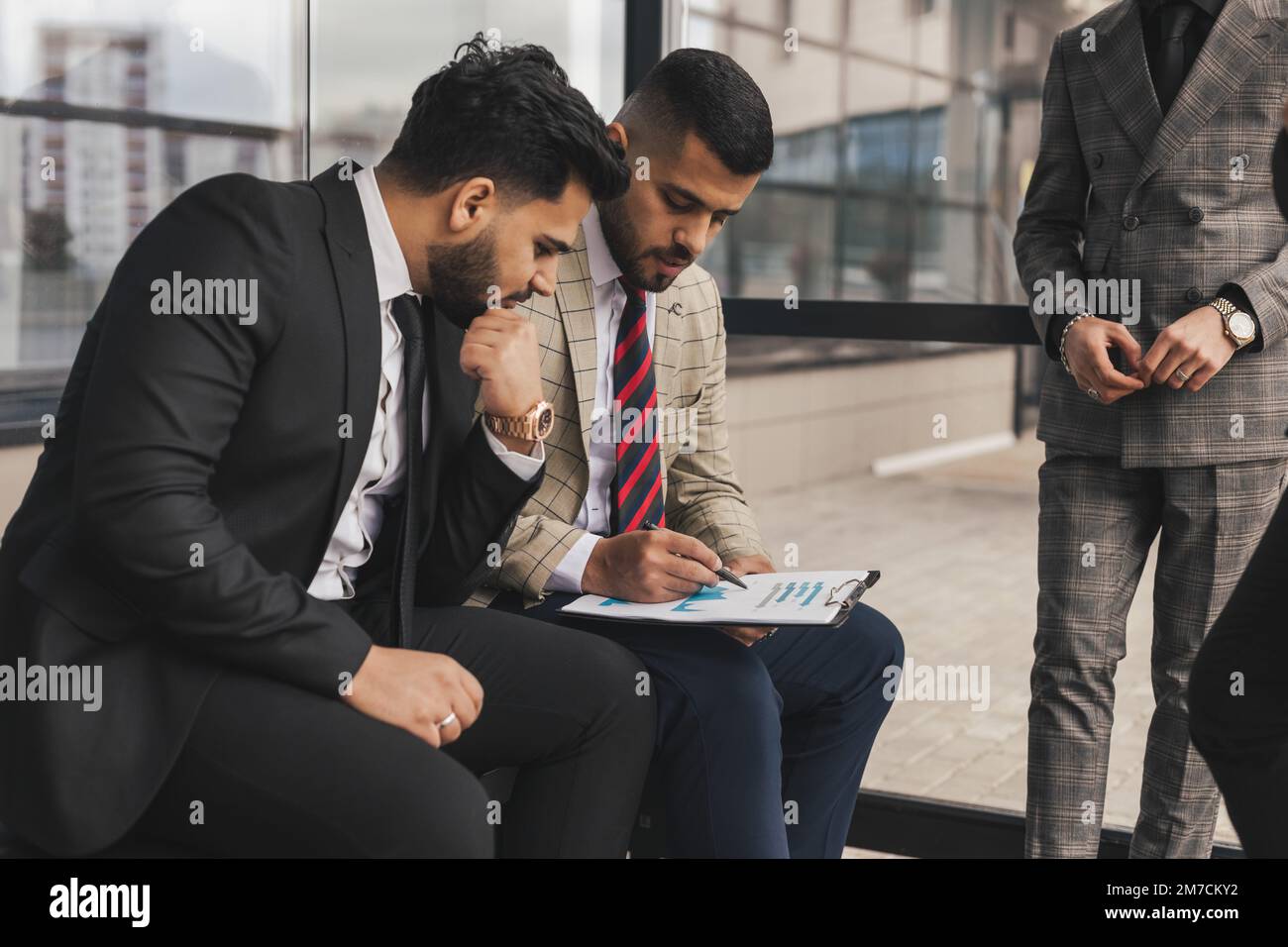 Business people outdoor meeting. Men in jackets discuss working moments ...