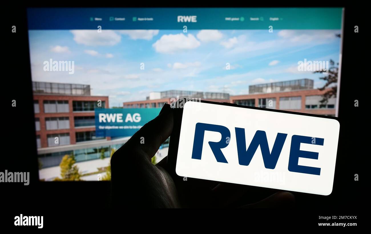 Person holding smartphone with logo of German energy company RWE AG on screen in front of ...
