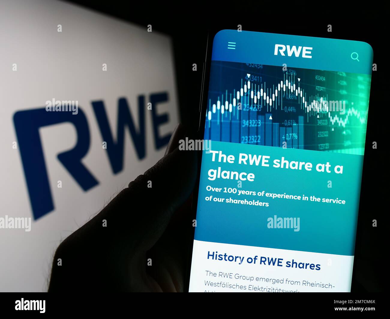 Person holding smartphone with website of German energy company RWE AG on screen in front of ...