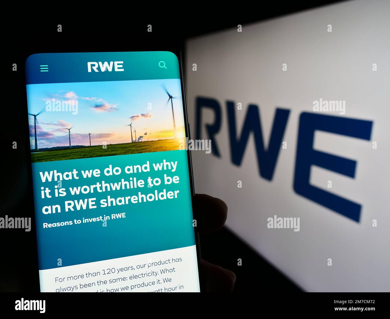Person holding mobile phone with webpage of German energy company RWE AG on screen in front of ...
