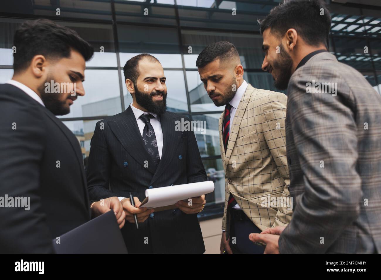 Business people outdoor meeting. Men in jackets discuss working moments ...