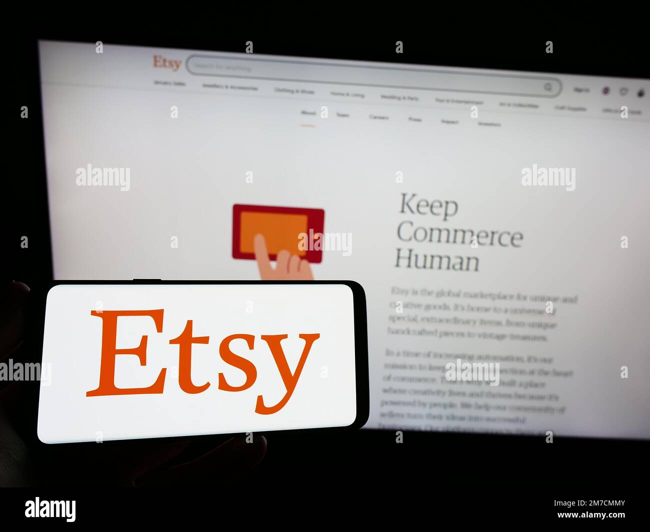 Person holding smartphone with logo of US e-commerce company Etsy Inc. on screen in front of ...