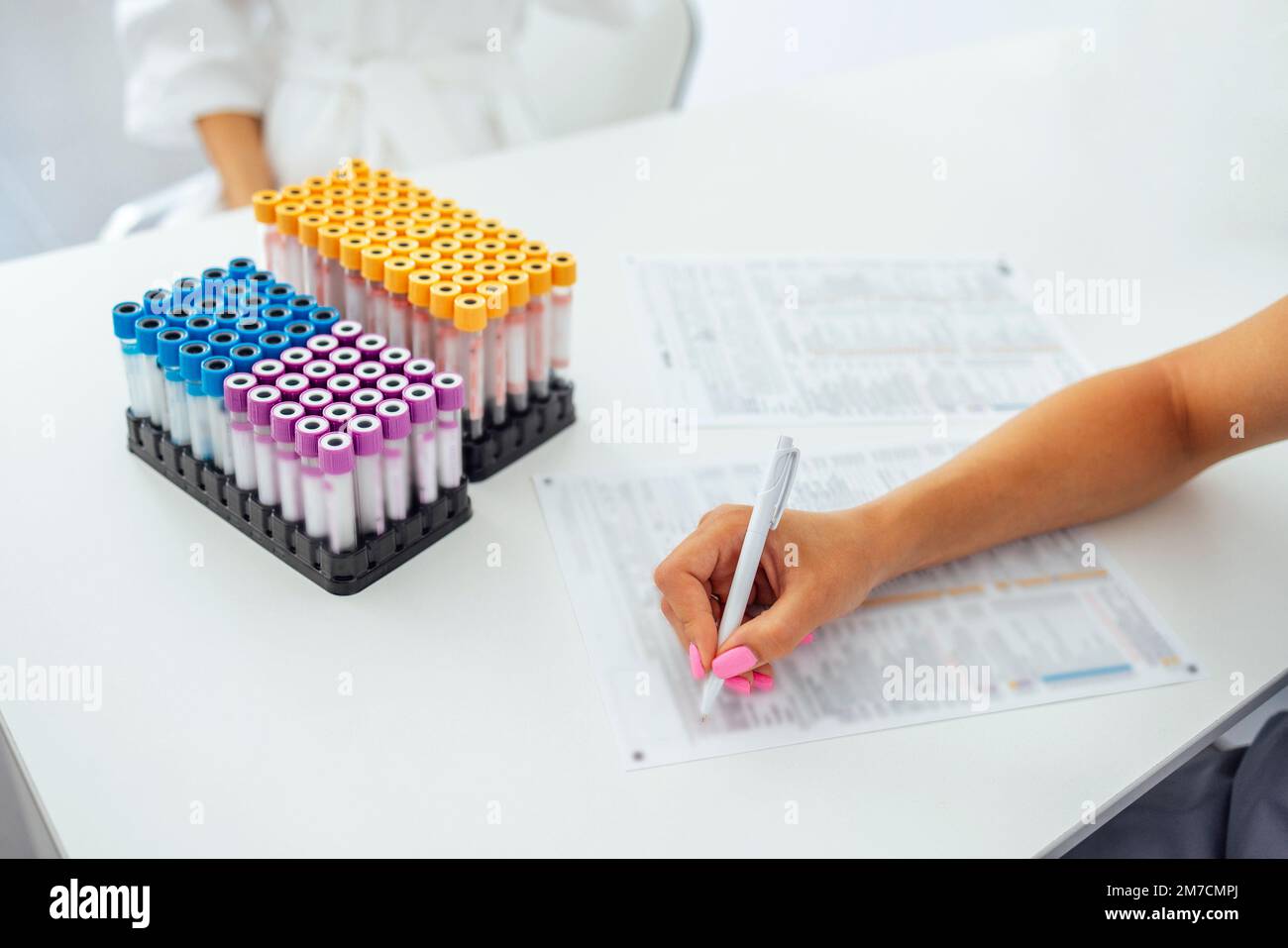 Female doctor writing check list of pacient with Blood test tubes on ...