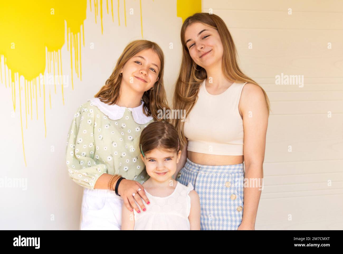 Three sisters of different ages have fun at home, hugging together ...