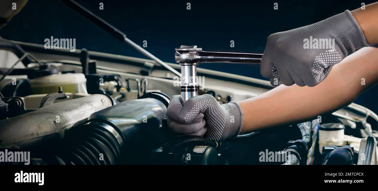 The mechanic works on the engine of the car in the garage, car repair ...
