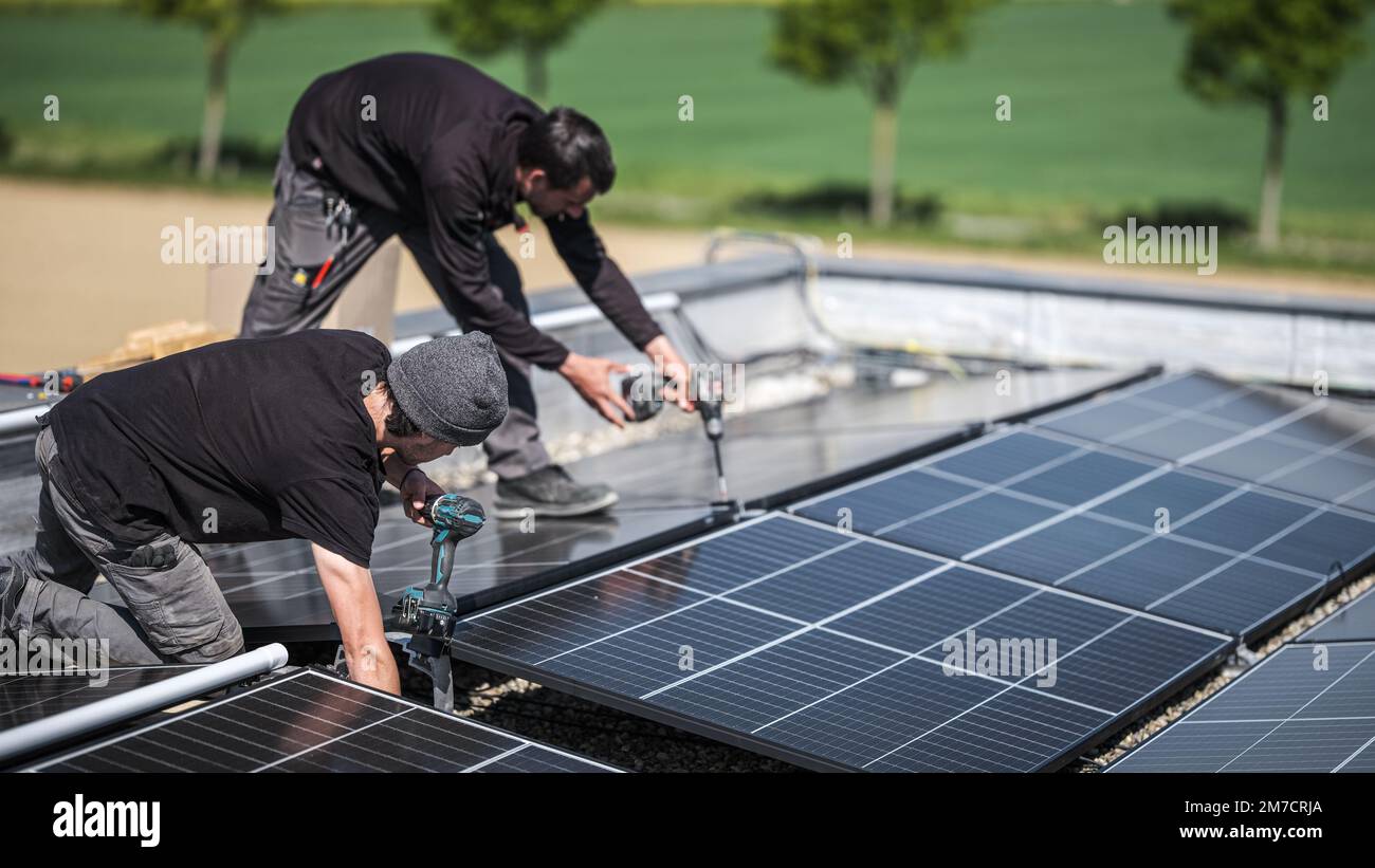 Male team engineers installing stand-alone solar photovoltaic panel ...
