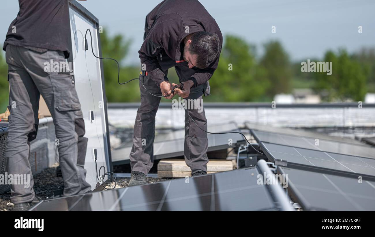 Male team engineers installing stand-alone solar photovoltaic panel ...