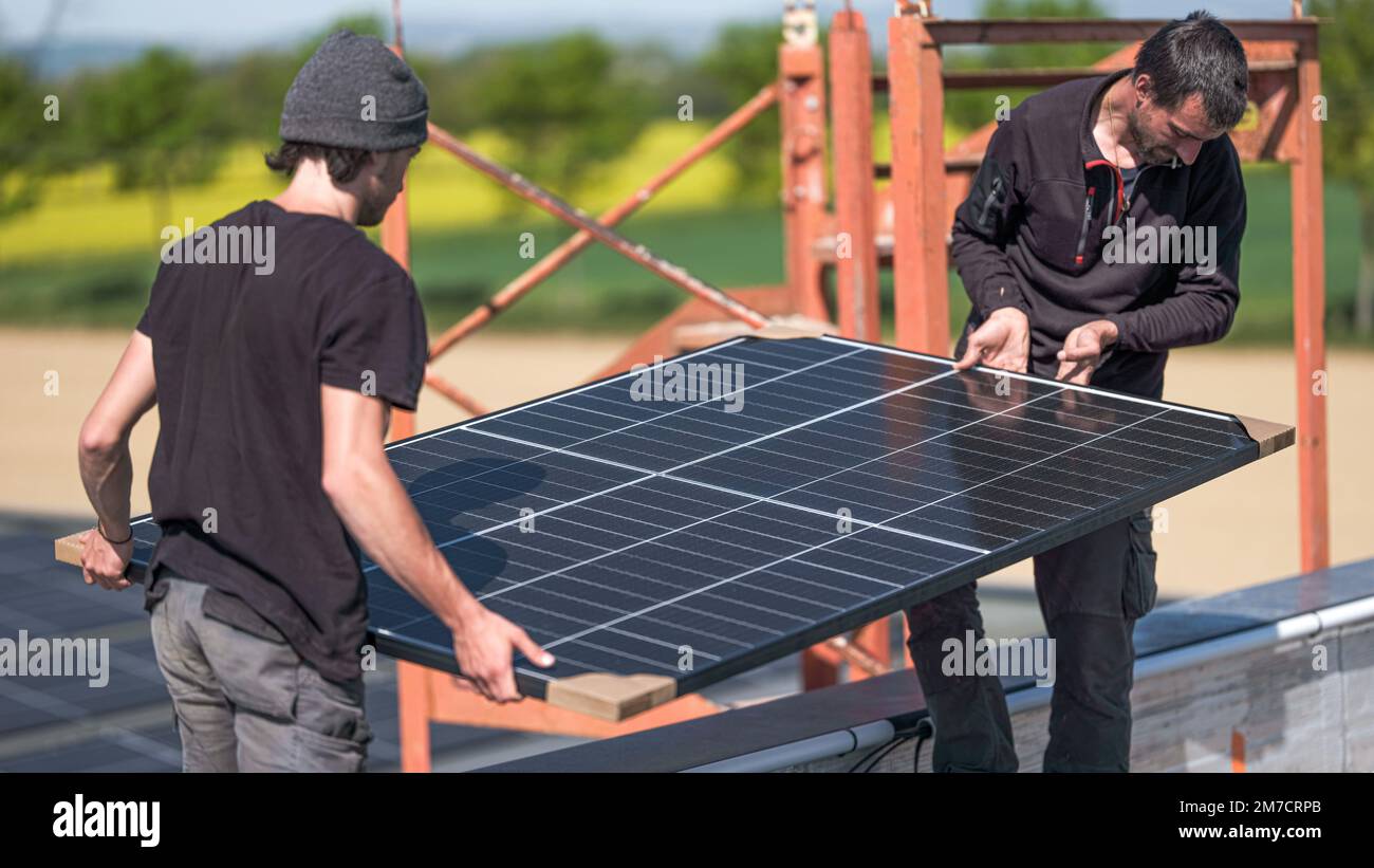 Male team engineers installing stand-alone solar photovoltaic panel ...