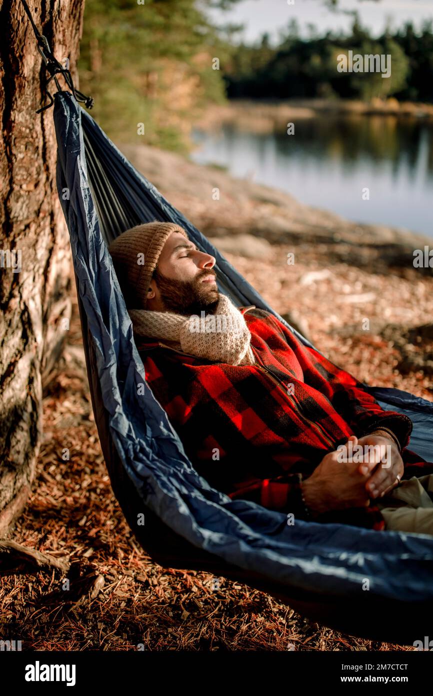 Man relaxing while lying down in hammock Stock Photo - Alamy