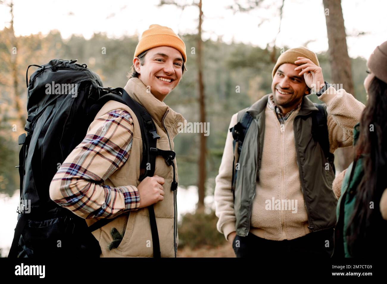 Side view portrait of smiling young man with backpack standing by ...