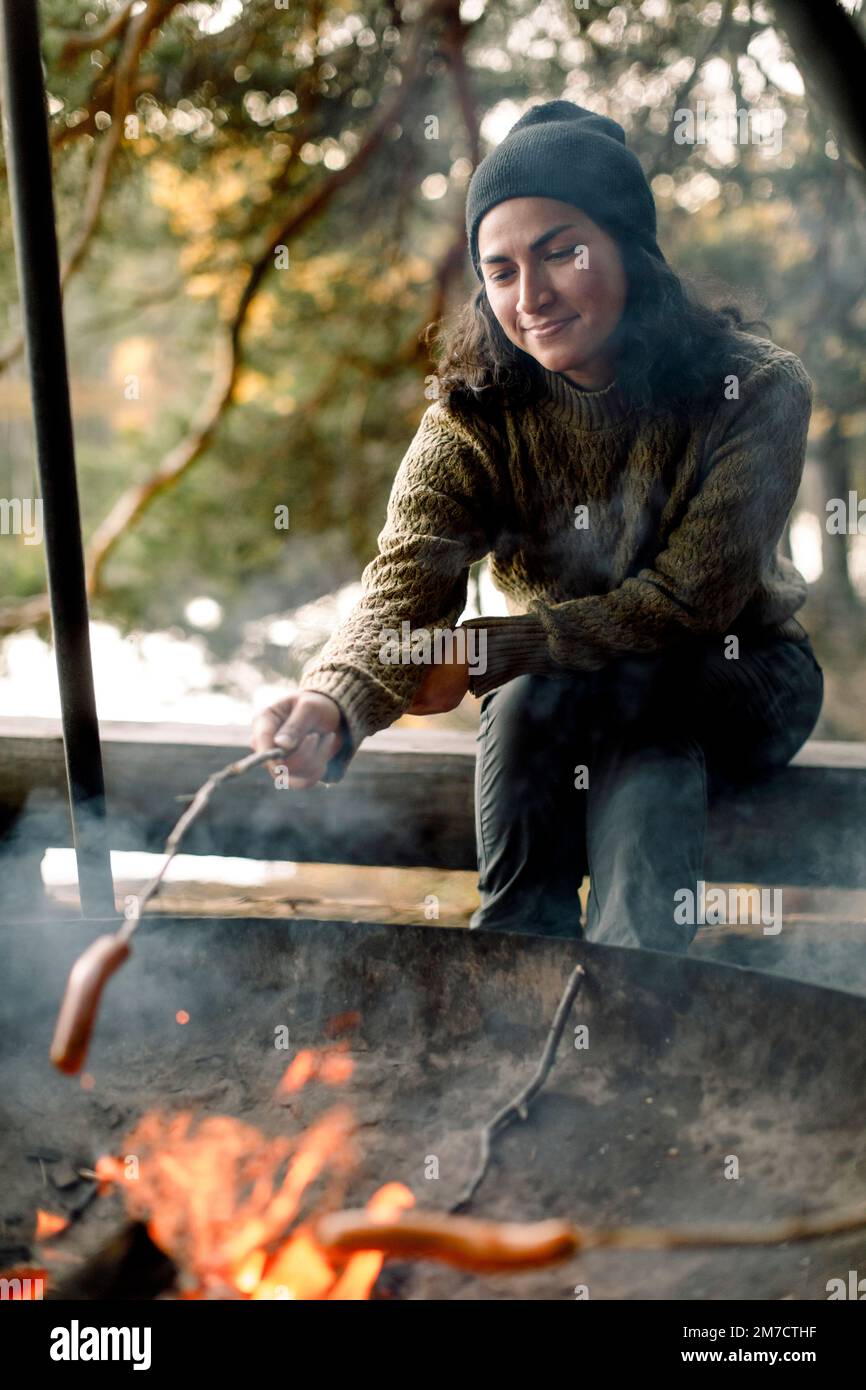 Woman roasting food over campfire during camping Stock Photo - Alamy