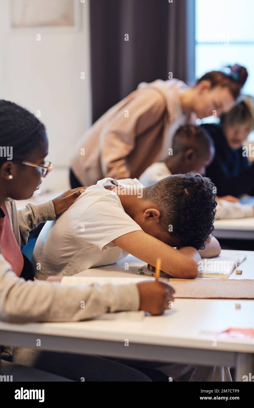 Teenage girl consoling depressed male student resting head on desk in ...