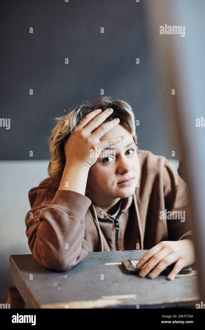 Portrait of teenage girl sitting with head in hands at desk Stock Photo ...