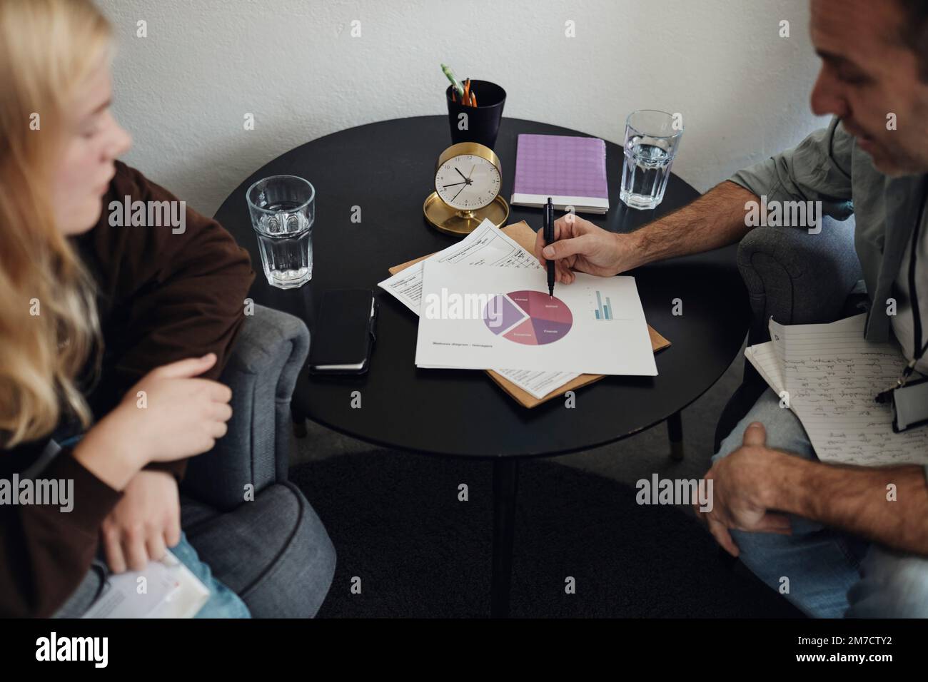Male counselor discussing over chart with female student in school ...