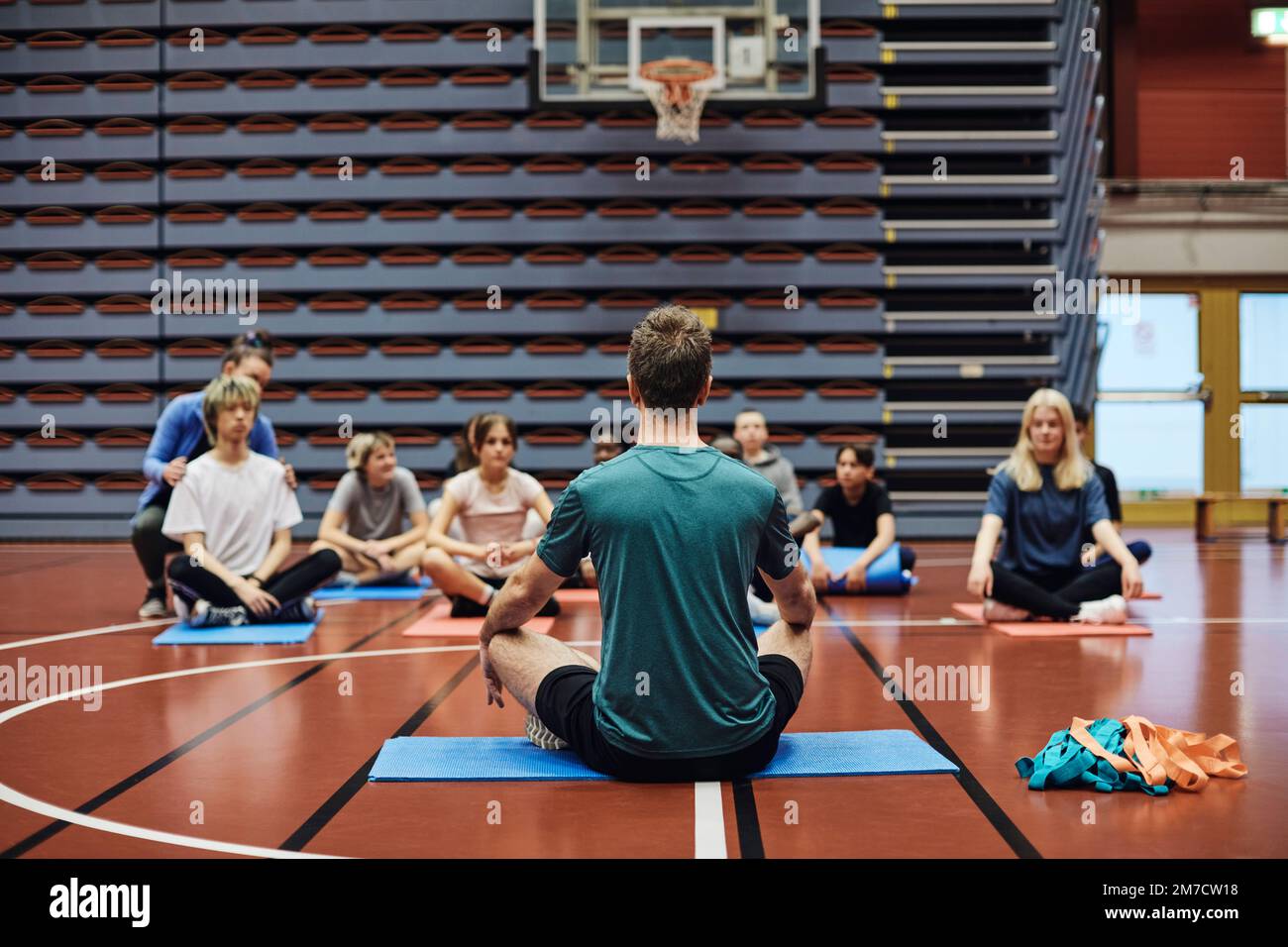 Male coach teaching exercise to students in sports court Stock Photo ...