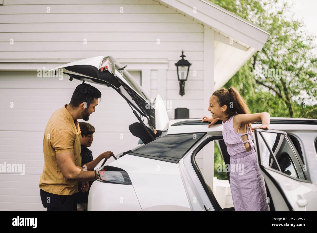 Smiling girl talking to father loading stuff in car trunk Stock Photo ...