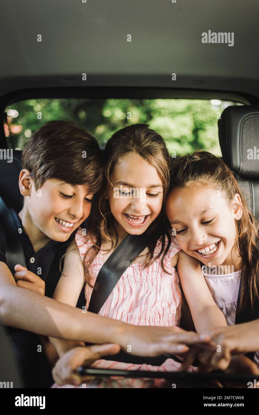Happy siblings sharing tablet PC while while traveling in car Stock ...