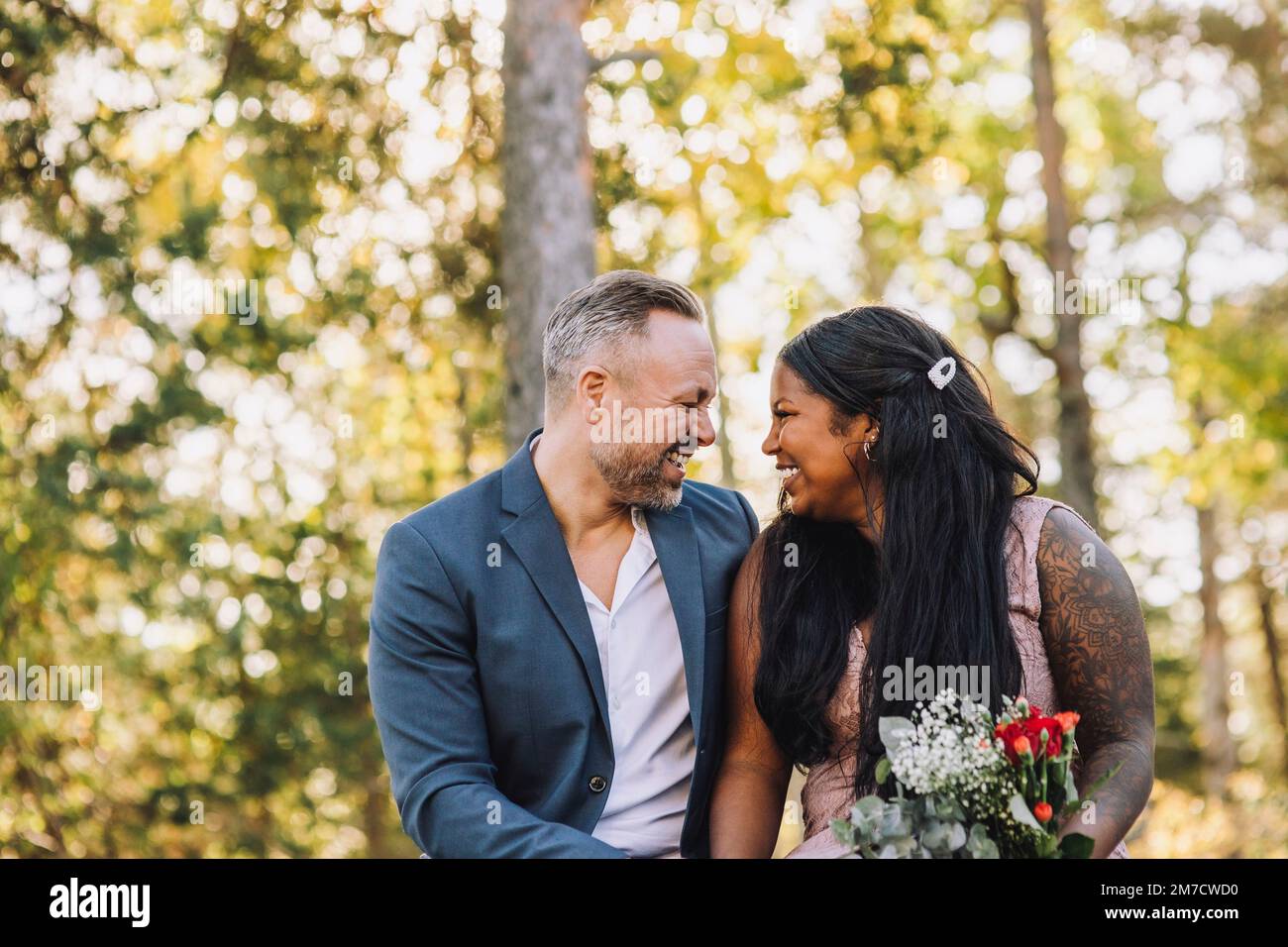 Happy groom looking at bride holding bouquet Stock Photo - Alamy