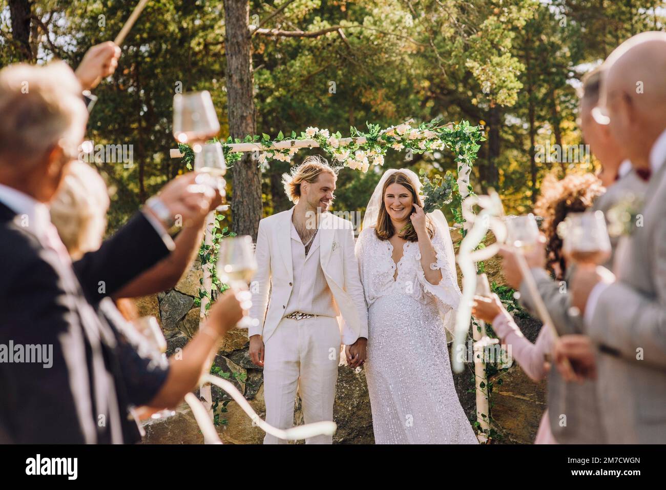 Happy bride and groom holding hands walking amidst guests at wedding ...