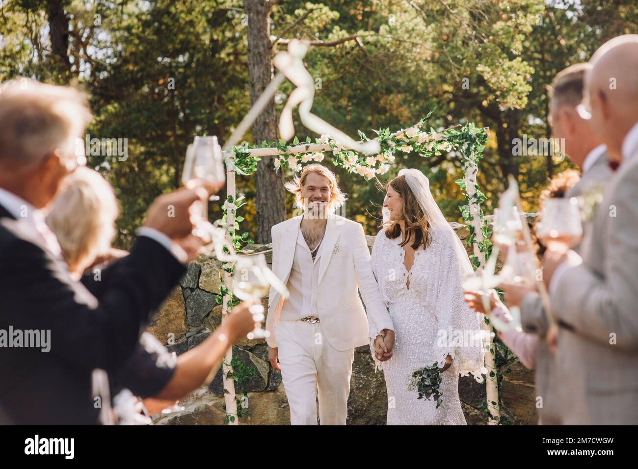 Newlywed mid adult couple holding hands walking amidst guests in ...