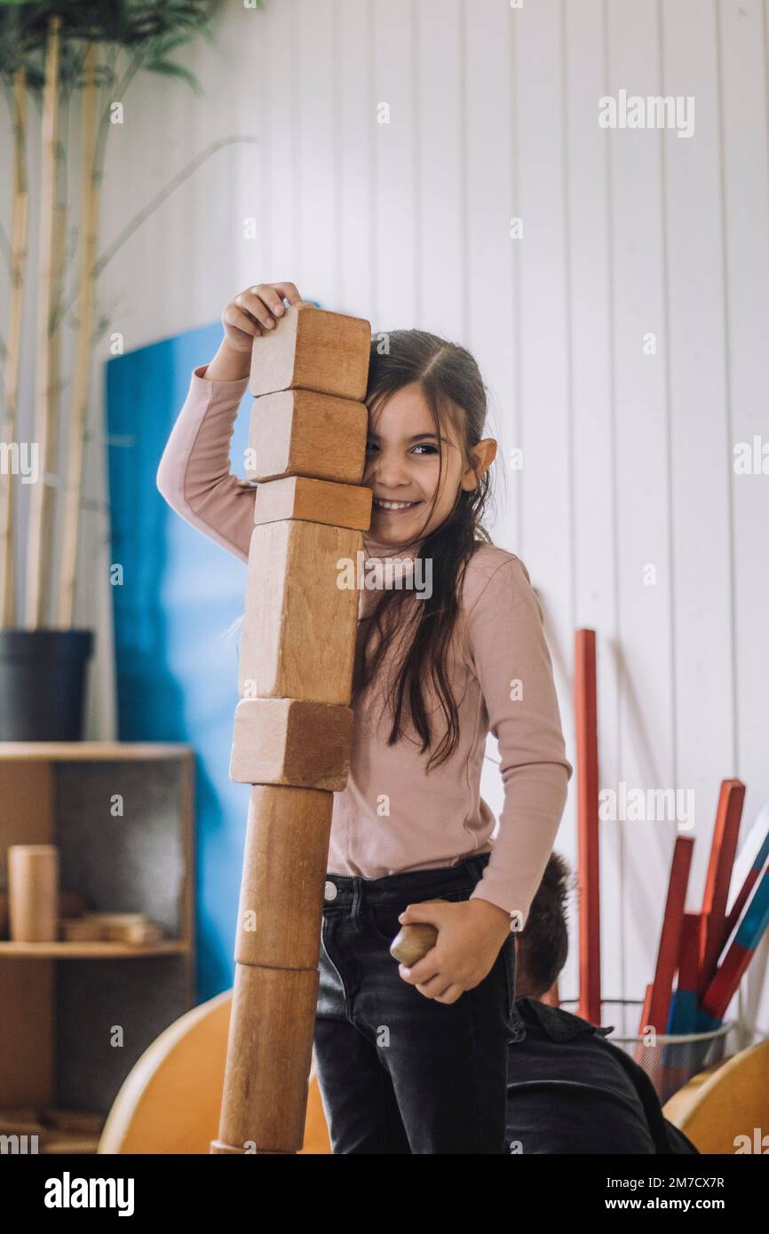 Smiling girl stacking wooden toy blocks in kindergarten Stock Photo - Alamy
