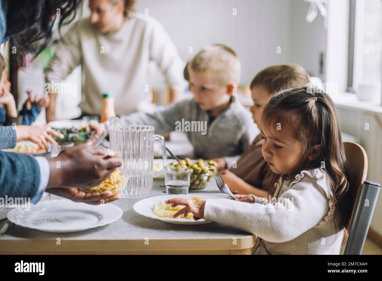 Teacher serving food to male and female students for breakfast in day ...