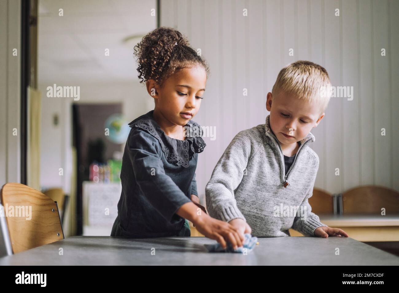 Multiracial male and female students cleaning dining table at ...