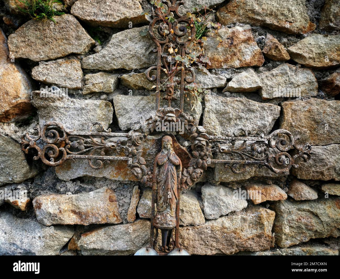 A closeup of an ancient metal Cemetery cross against a stone wall Stock ...