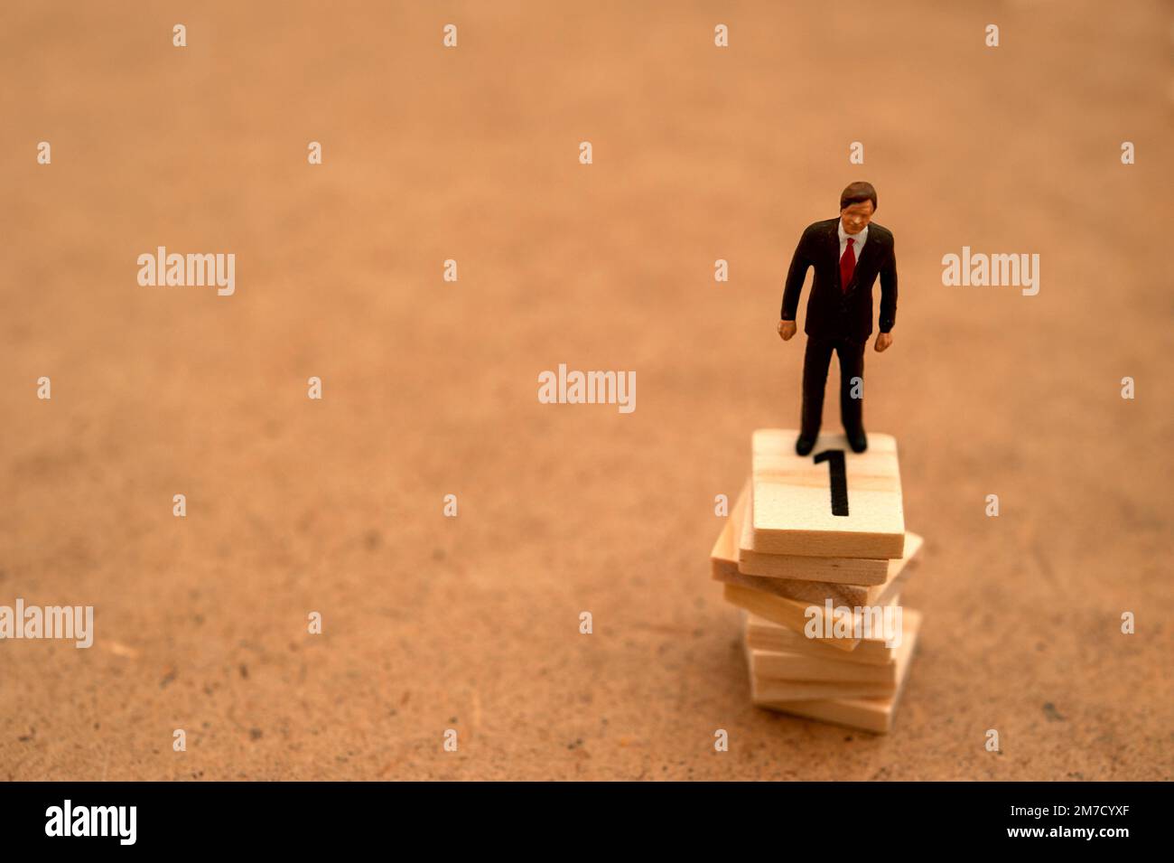 miniature figurine of a businessman standing on a pile of tiles, with ...