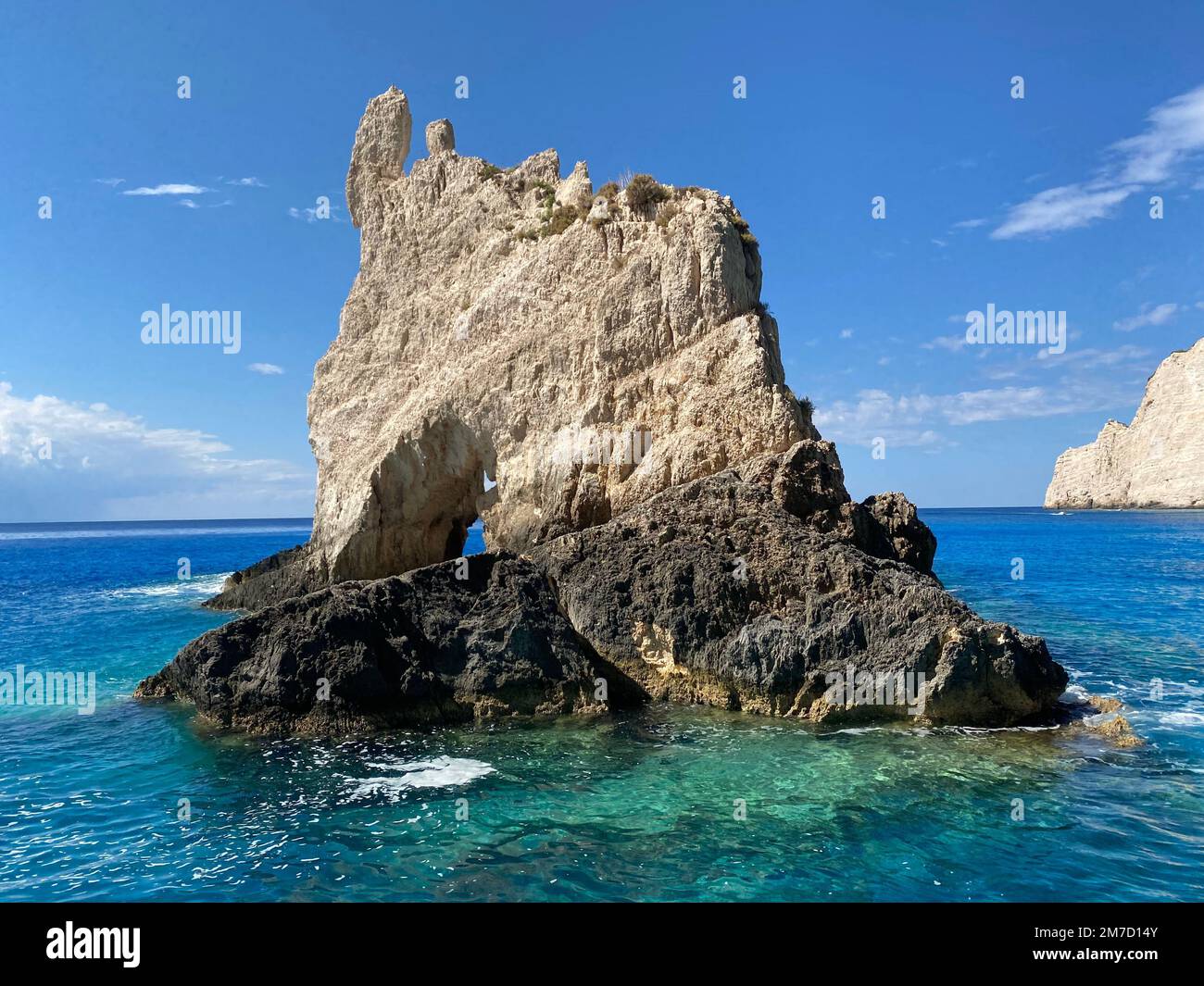 A cliff in the greenish blue sea against the background of the sky ...