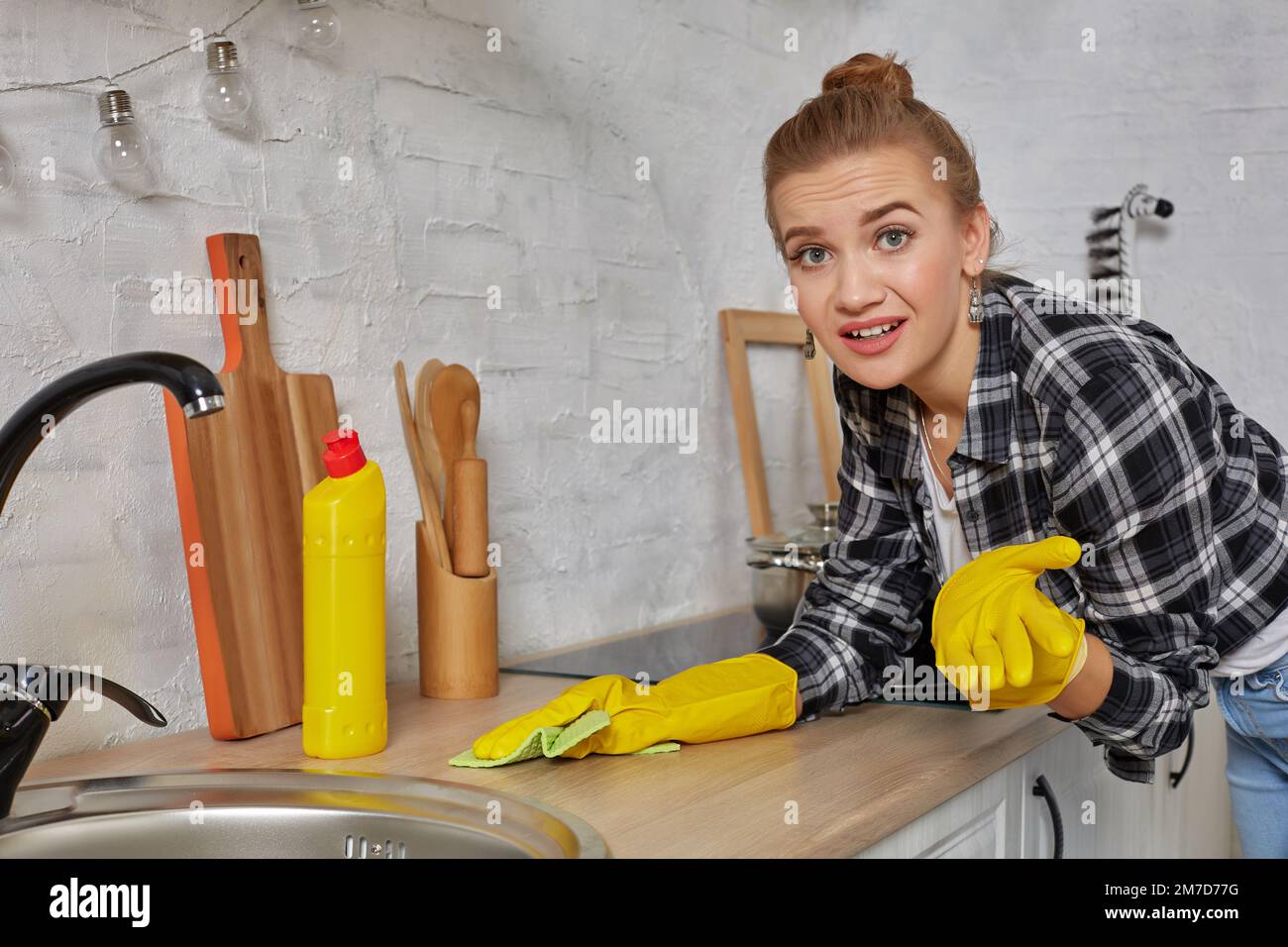 Young woman washing manually, by hand, wearing yellow cleaning rubber ...