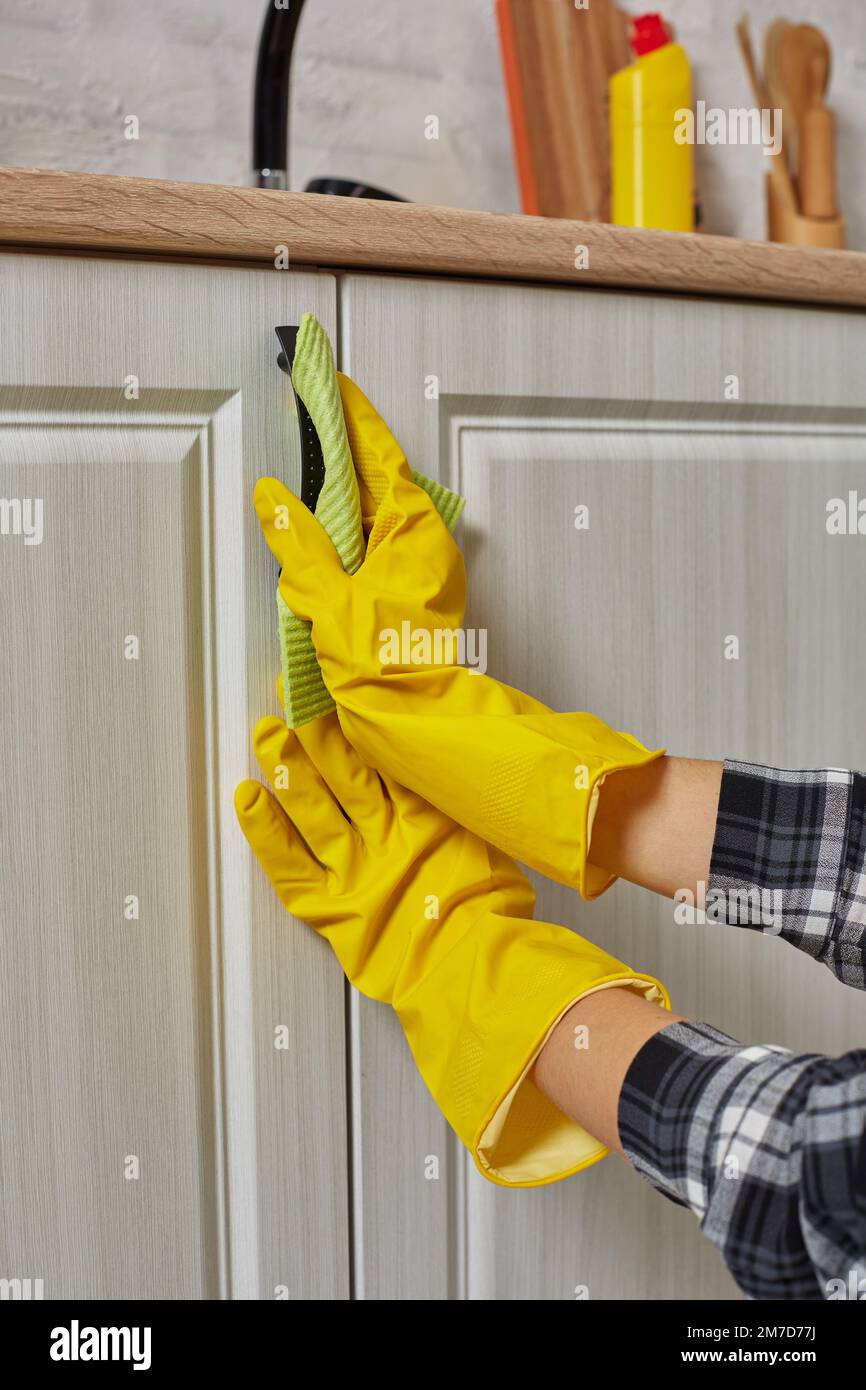 Hands in gloves with green rag is cleaning kitchen cabinets - housework ...