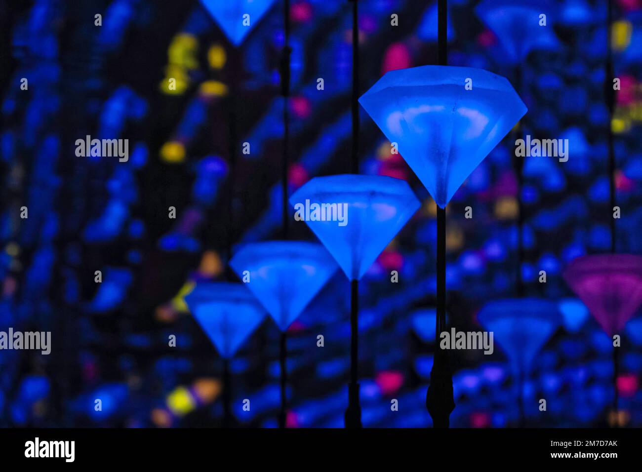 A closeup of beautiful colorful neon diamond gears hanging on ropes in ...