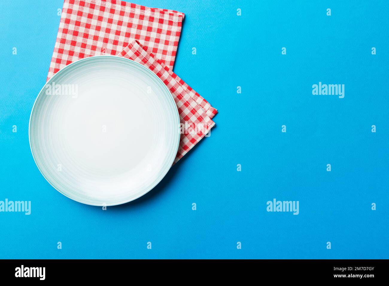 Top view on colored background empty round Blue plate on tablecloth for ...