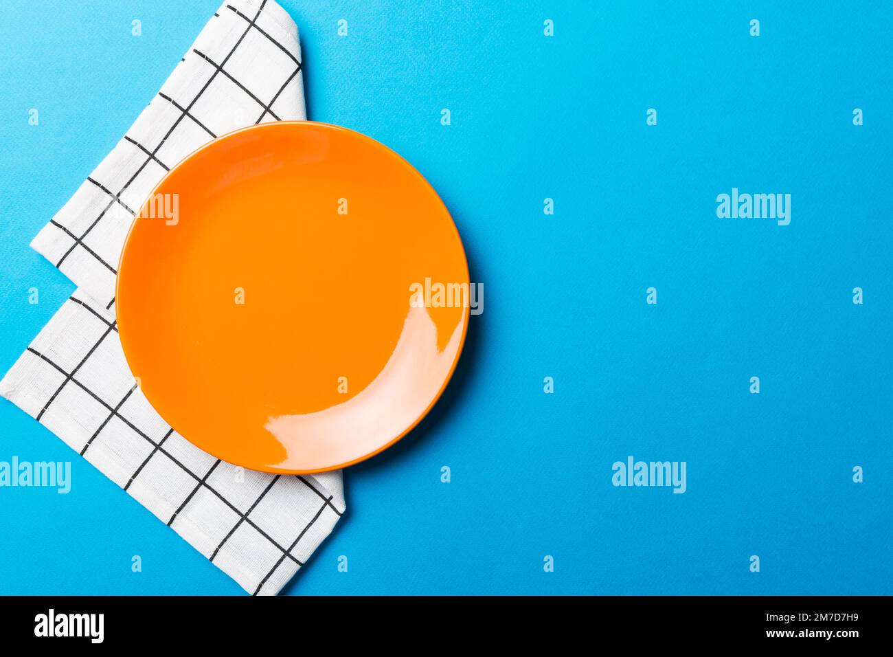 Top view on colored background empty round red plate on tablecloth for ...