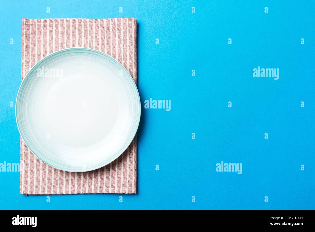 Top view on colored background empty round Blue plate on tablecloth for ...