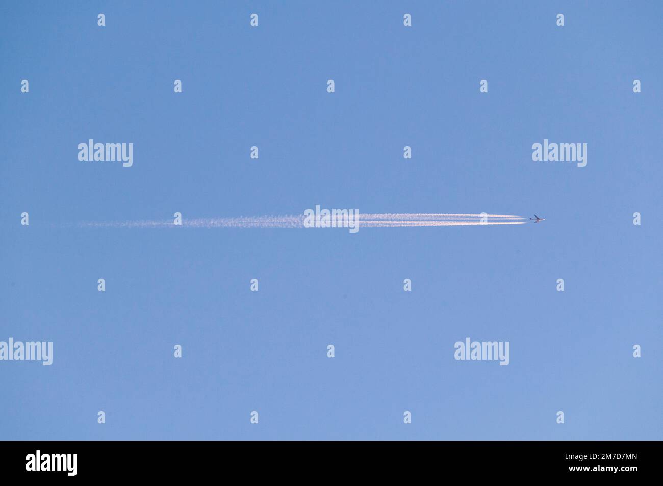 A jet aeroplane passes way overhead leaving a fine vapor trail across ...