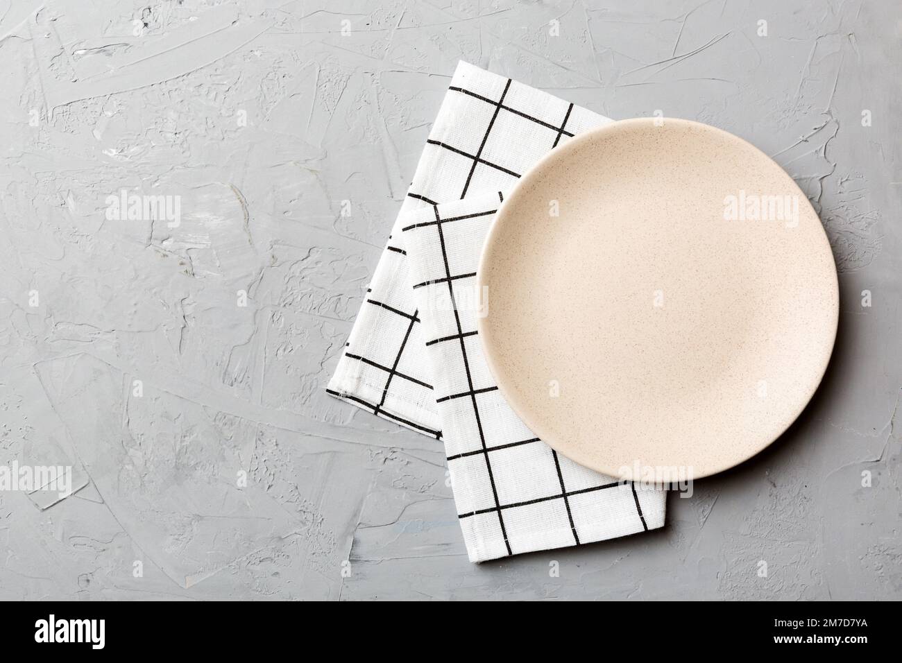 Top view on colored background empty round white plate on tablecloth ...