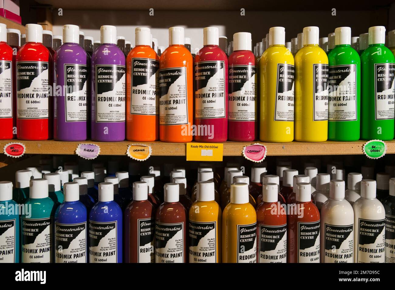 Lines of paints and coloured media stacked on shelves in an artists ...