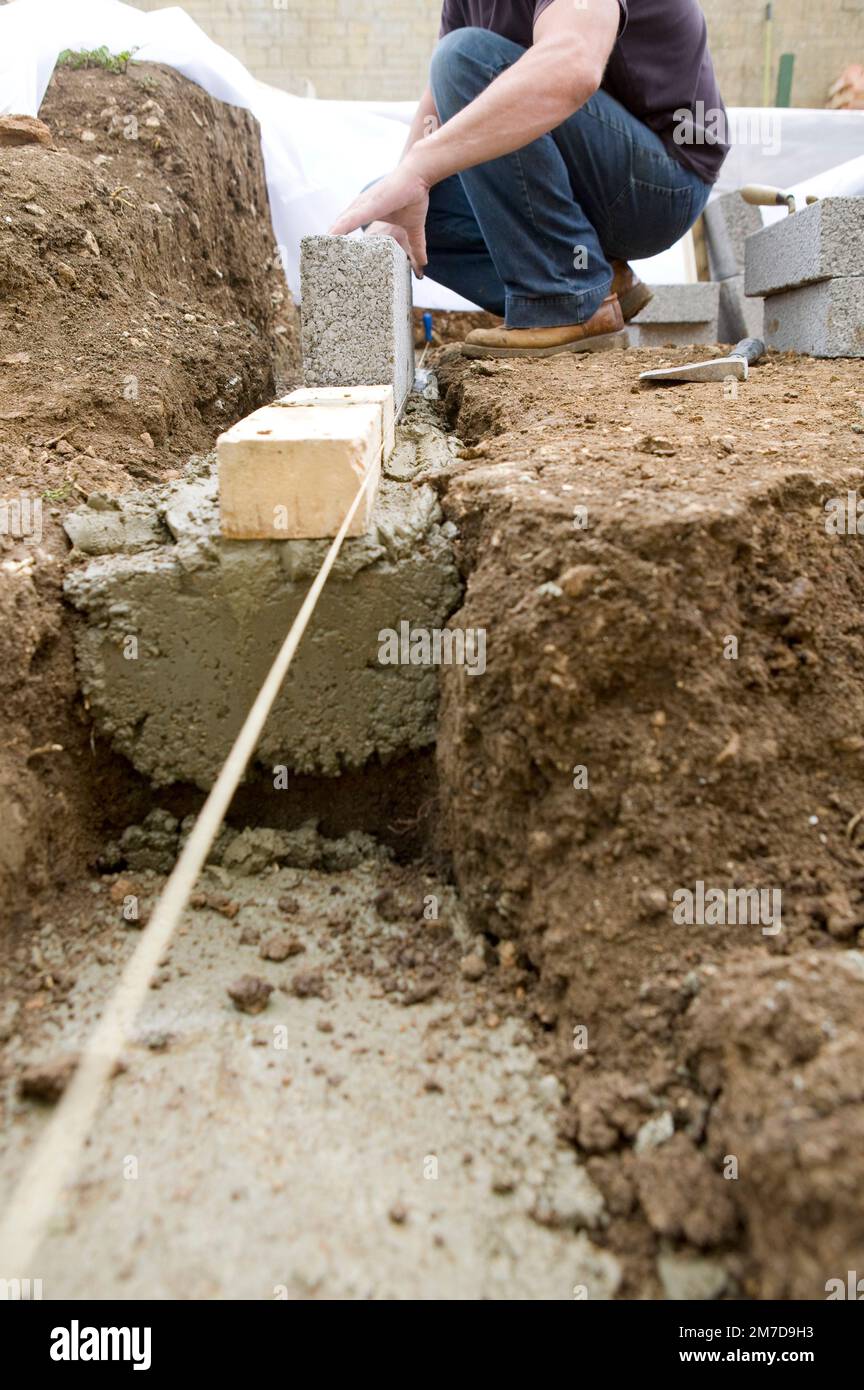 Laying a new wall in a freshly landscaped garden, firstly with a layer ...