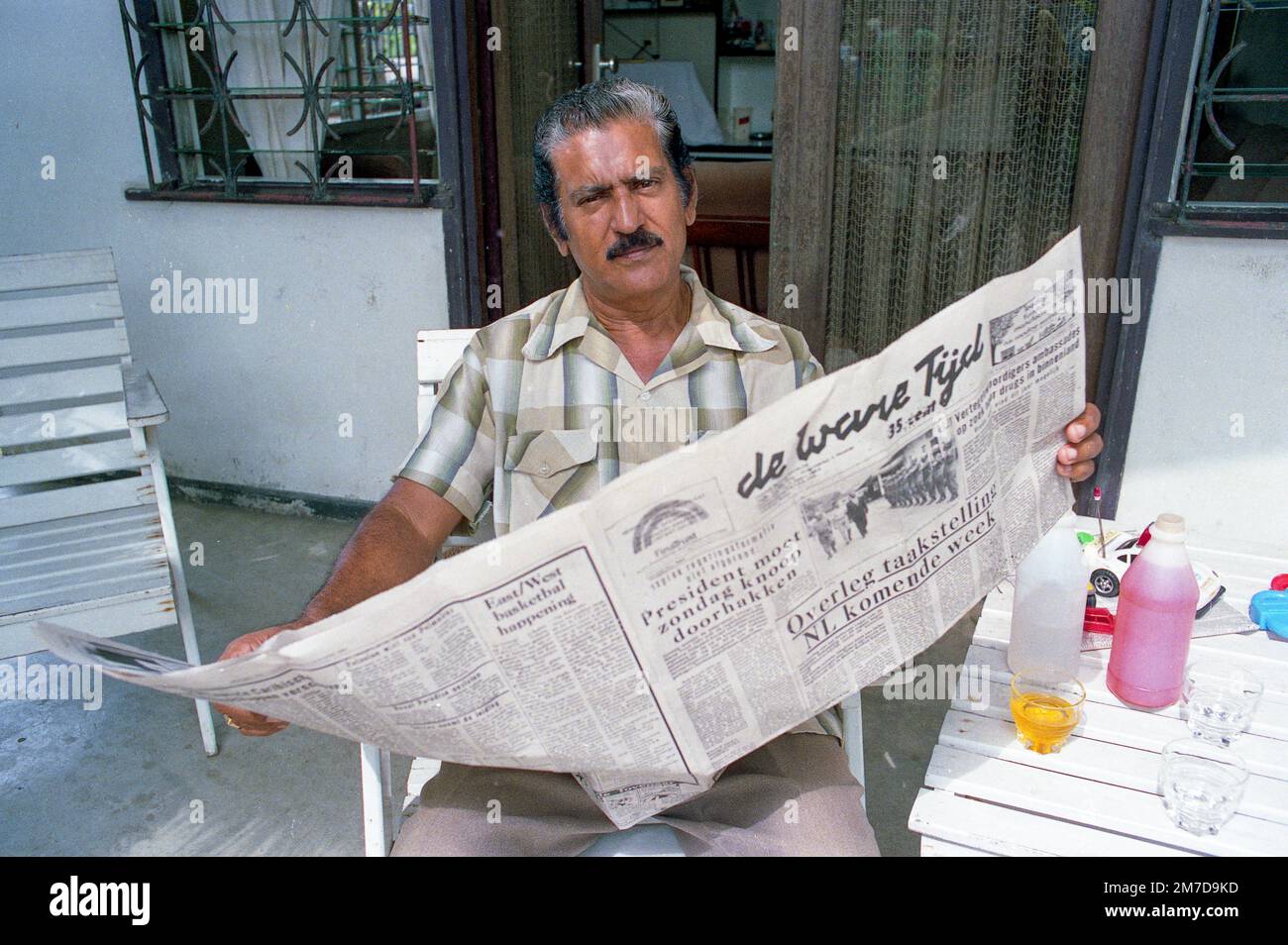 Surinam, Paramaribo. Man is reading one of the two national newspapers ...
