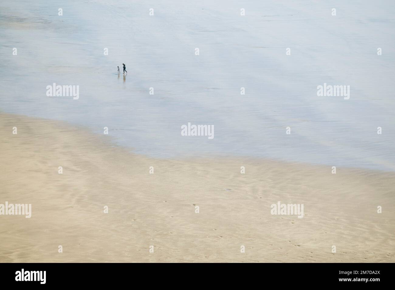 A tiny figure with shadow is silhouetted on the sand of a vast empty ...