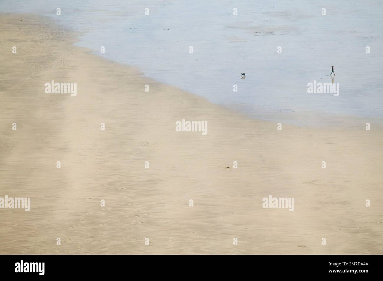 A tiny figure with shadow is silhouetted on the sand of a vast empty ...