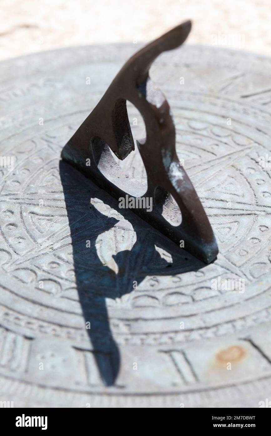 A traditional sundial arm sitting on its stone plinth and casting its ...