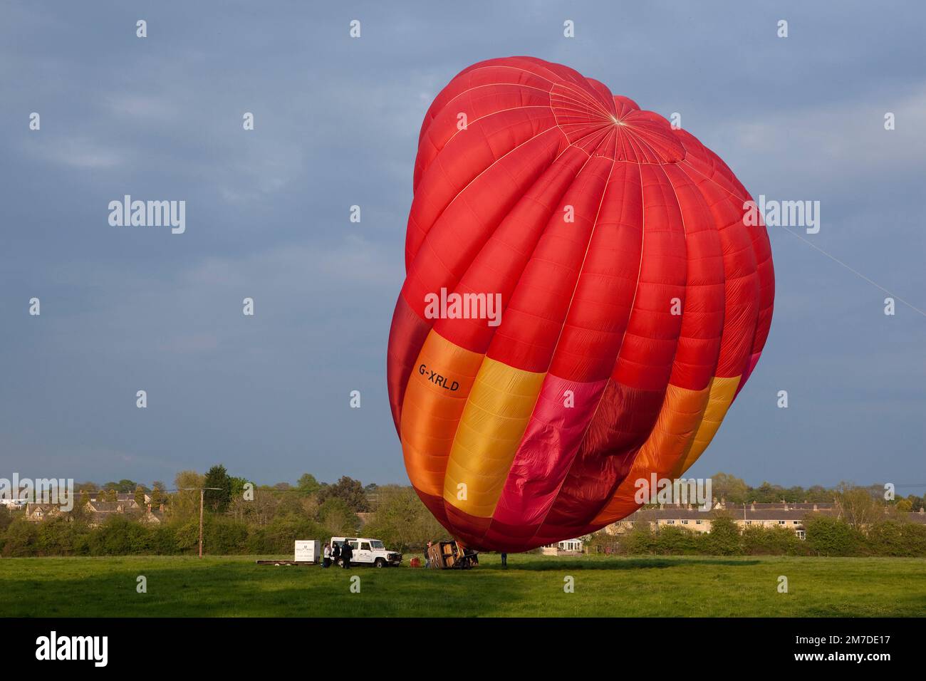 A Bright Red Hot Air Ballon Lifts Off From A Field On The Cotswolds Taking Passengers On A