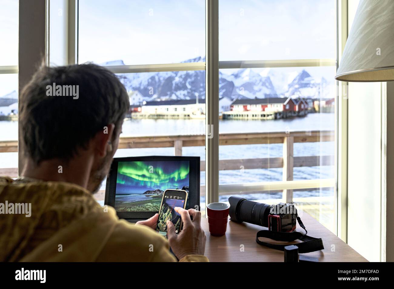 Tourist smartworking inside a traditional Rorbu house, Lofoten islands ...