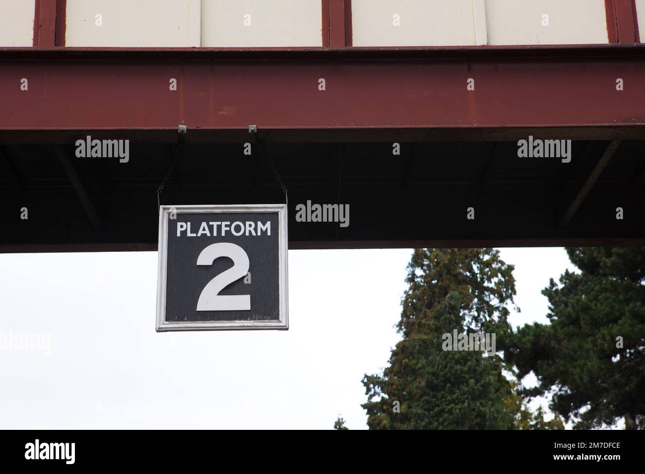 A small sign hanging froma bridge at a station indicating the number of ...