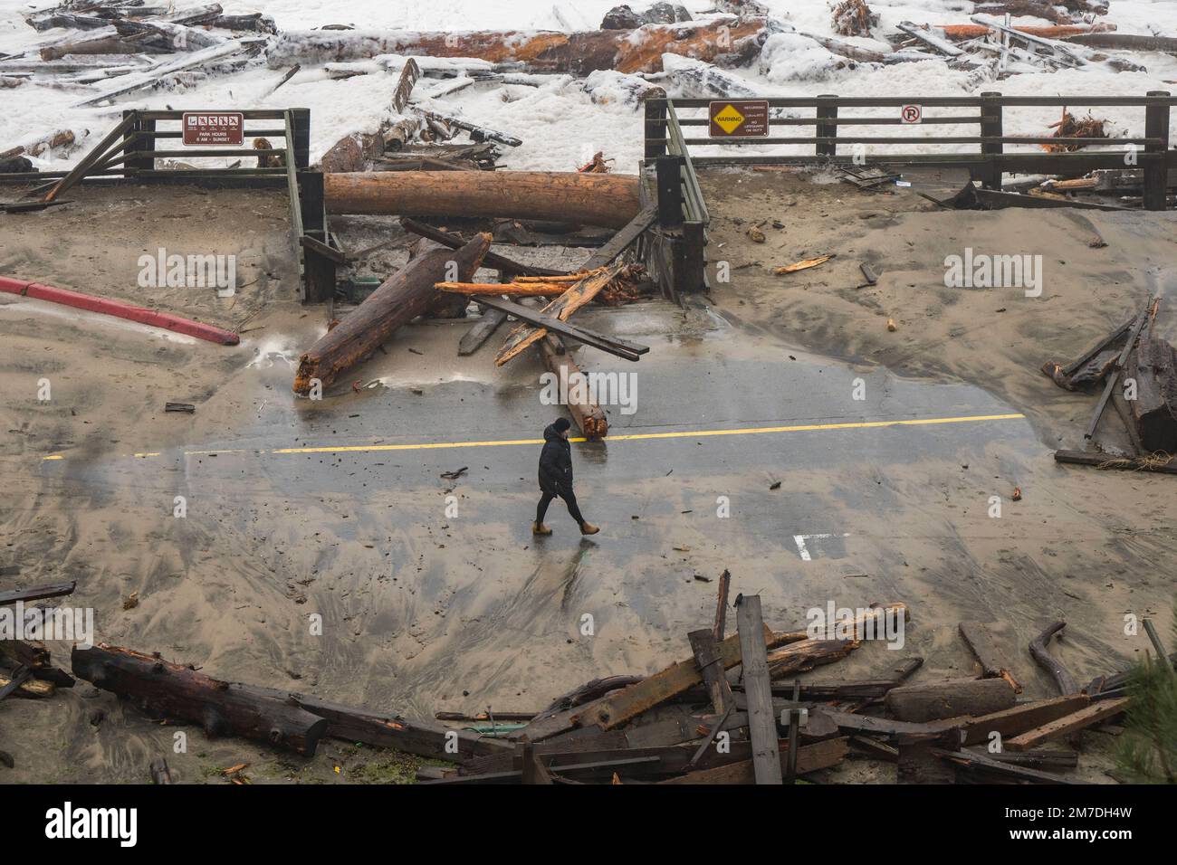A California State Parks employee walks through a damaged road at ...